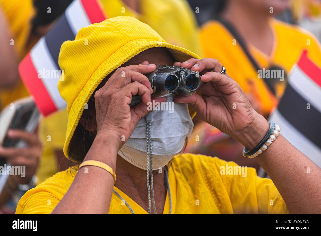 A spectator uses a binocular to see the royal barge down the Chao ...