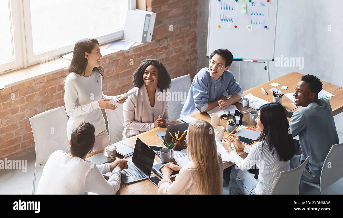 Enthusiastic girl sharing her ideas with cheerful colleagues while ...