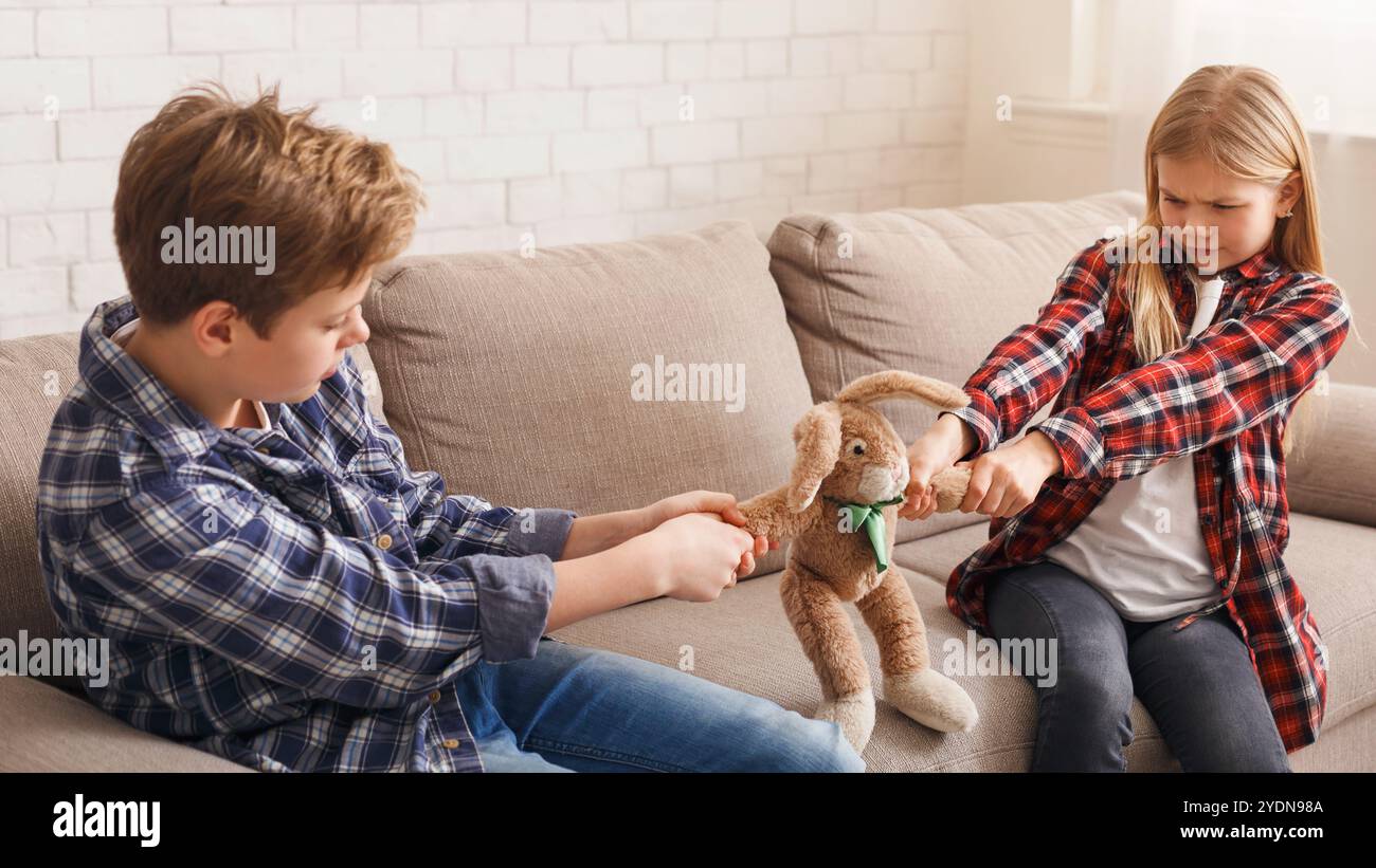 Greedy Brother And Sister Pulling Apart Toy Sitting On Sofa Stock Photo ...