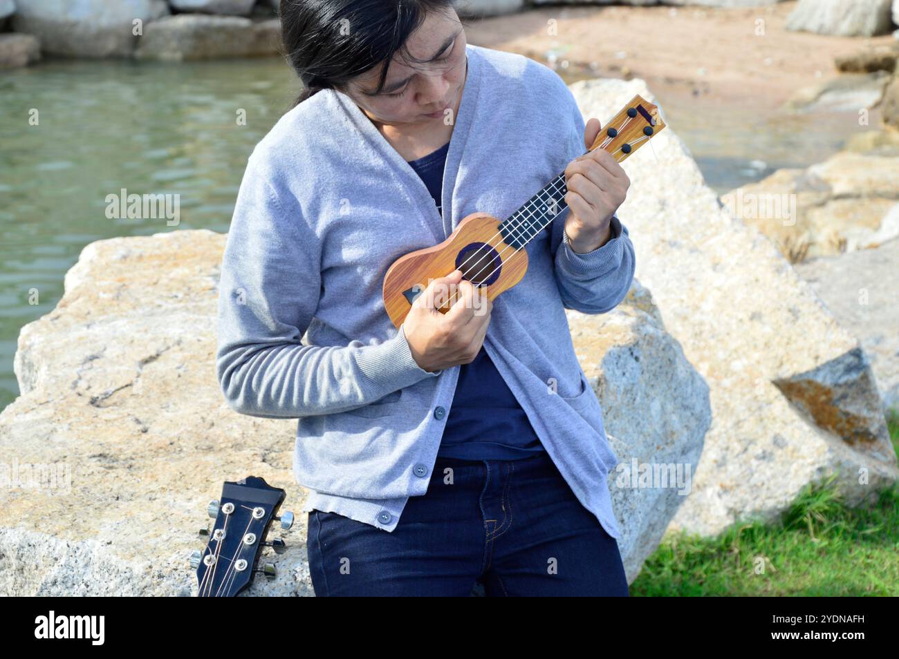 Front view of Asian woman playing ukulele Stock Photo - Alamy