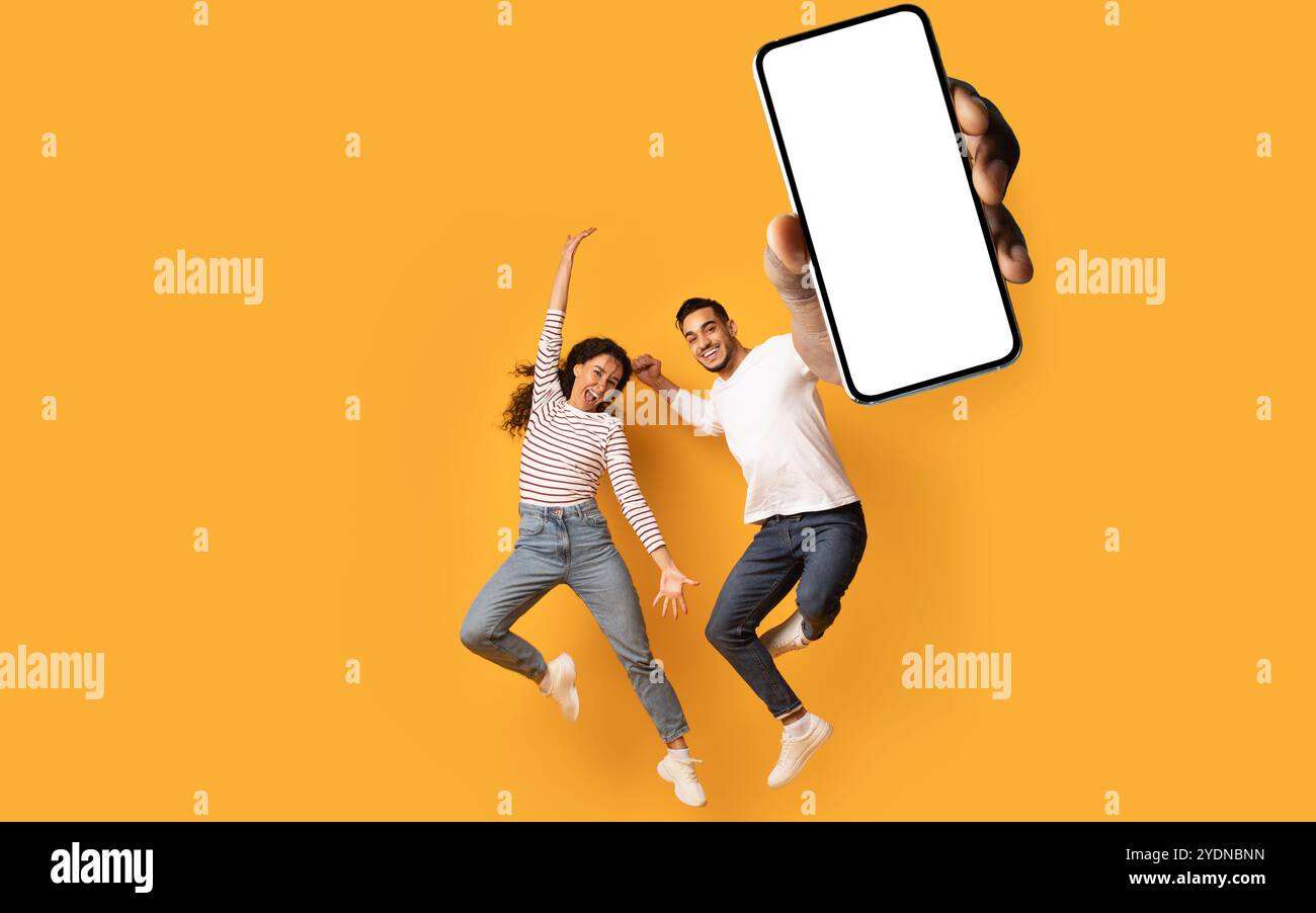 Wow, great news. Overjoyed couple showing huge smartphone with blank ...