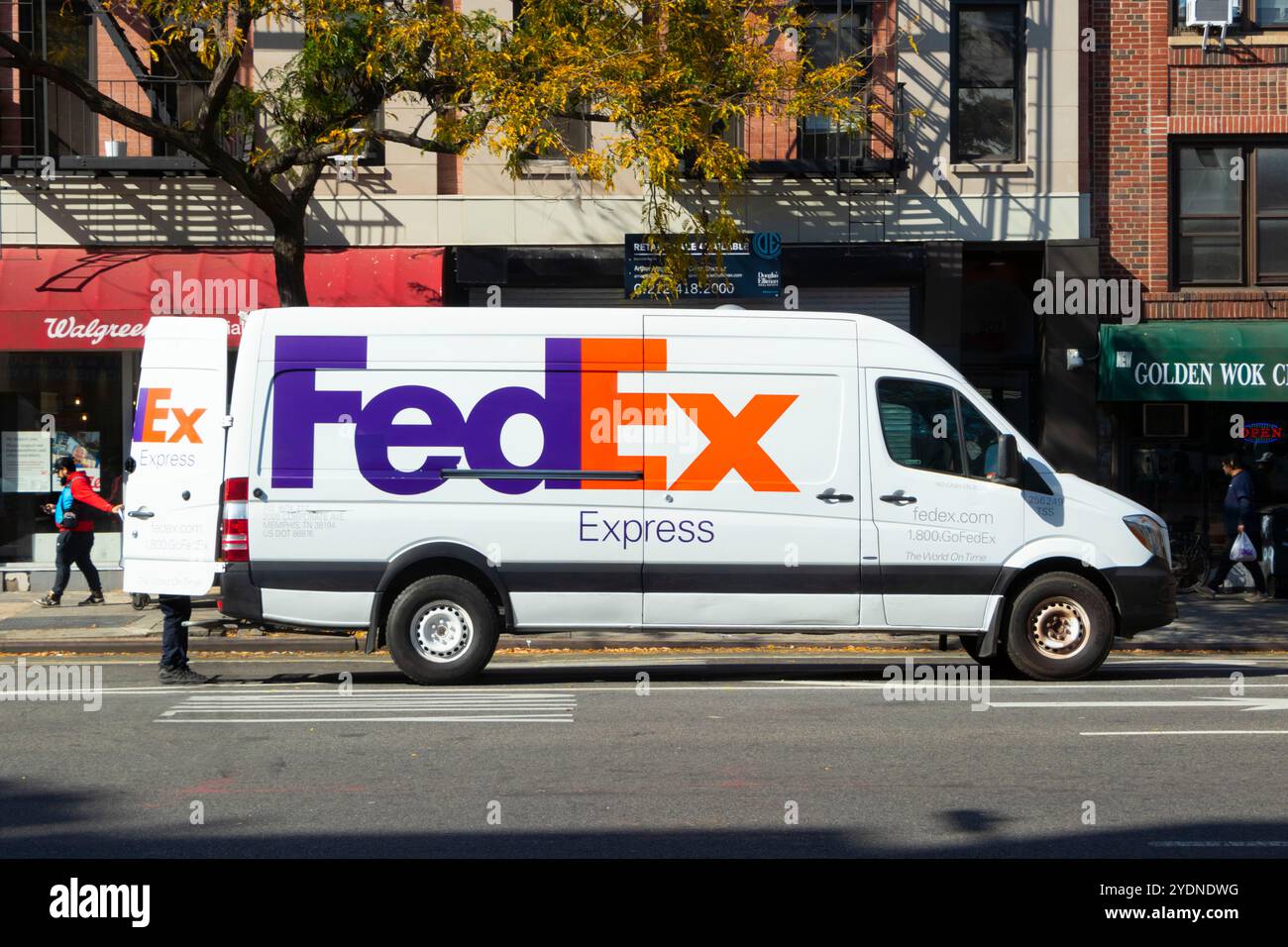 FedEx delivery van parked on a city street with storefronts and ...