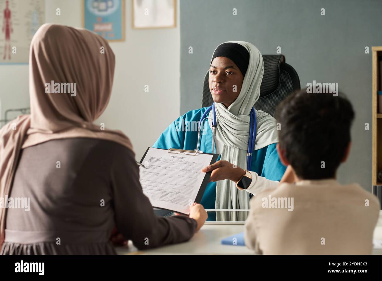 Muslim healthcare professional wearing hijab discussing medical records ...