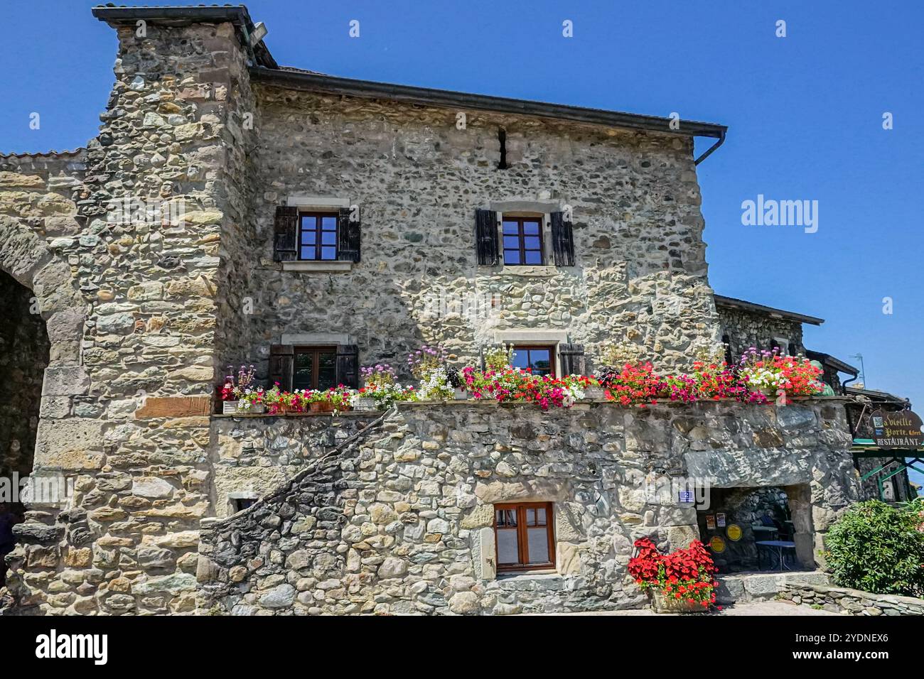 A profusion of flowers spill from a balcony of a stone building in the ...