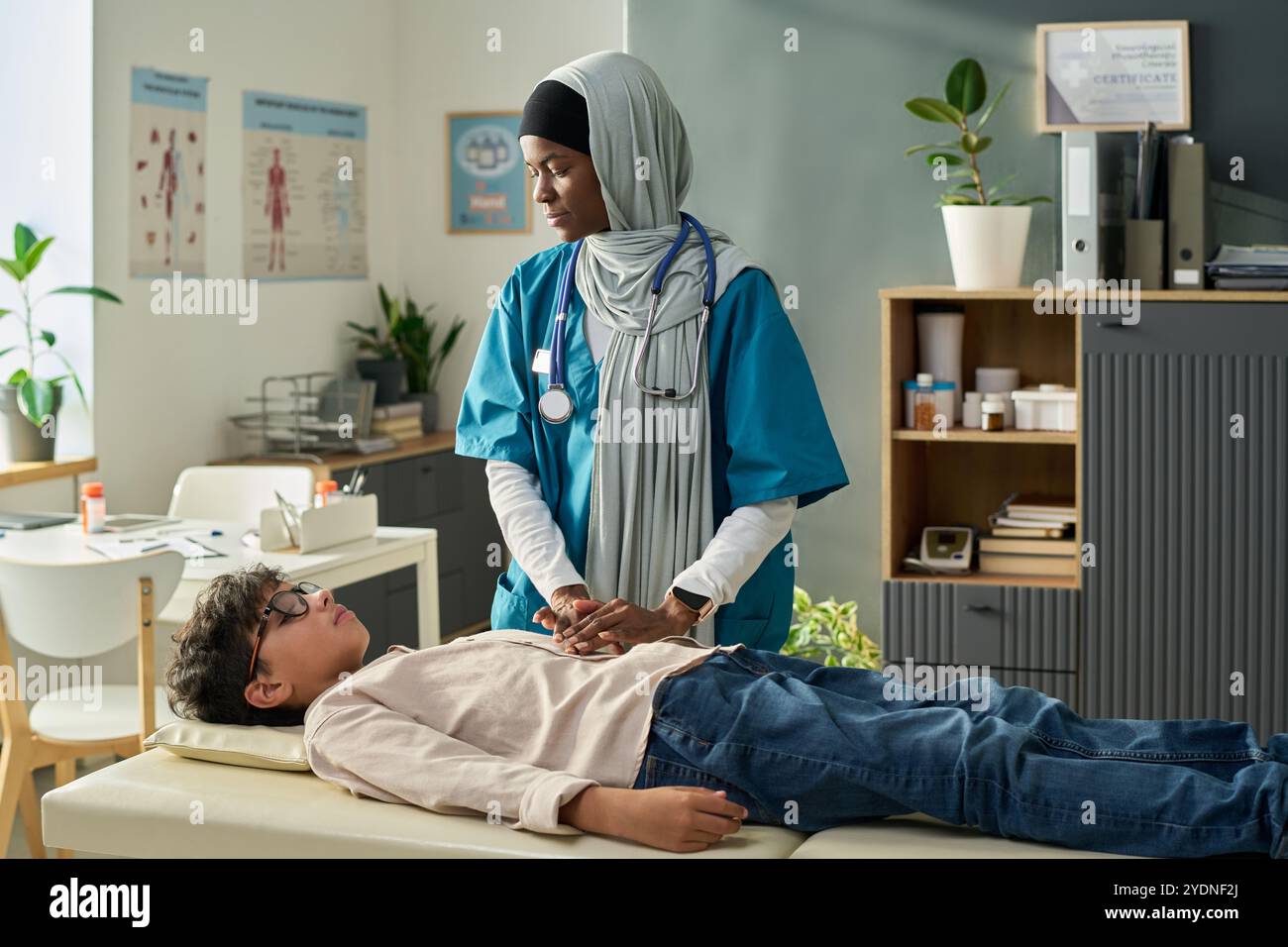 Muslim healthcare professional wearing stethoscope attending to young ...