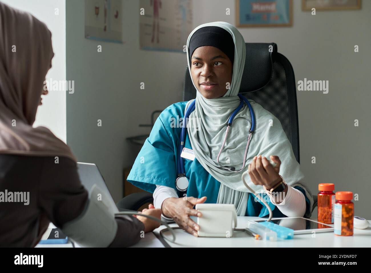 Muslim healthcare professional in hijab checking blood pressure of ... Muslim healthcare professional in hijab checking blood pressure of ...