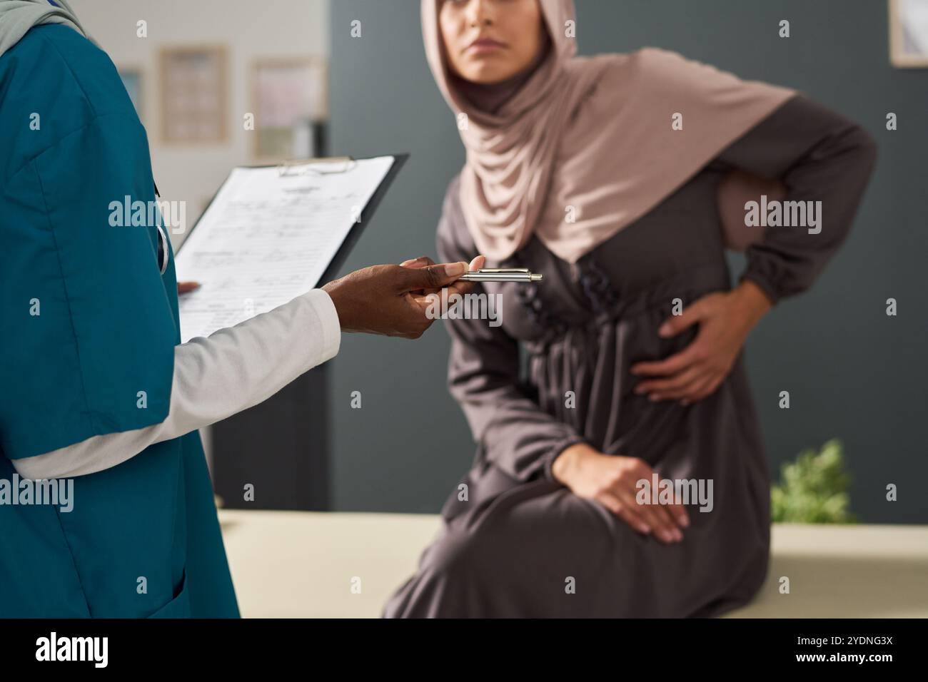 Muslim female patient wearing hijab sitting in clinic during medical ...