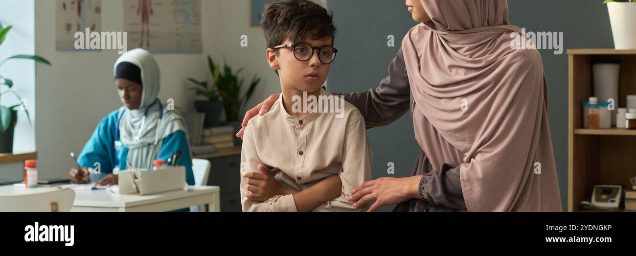 Muslim teacher in hijab gently consoling young student in classroom ...