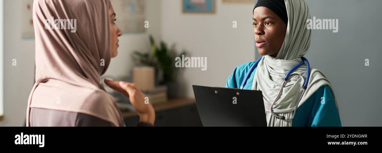 Two Muslim women engaging in conversation in medical environment ...