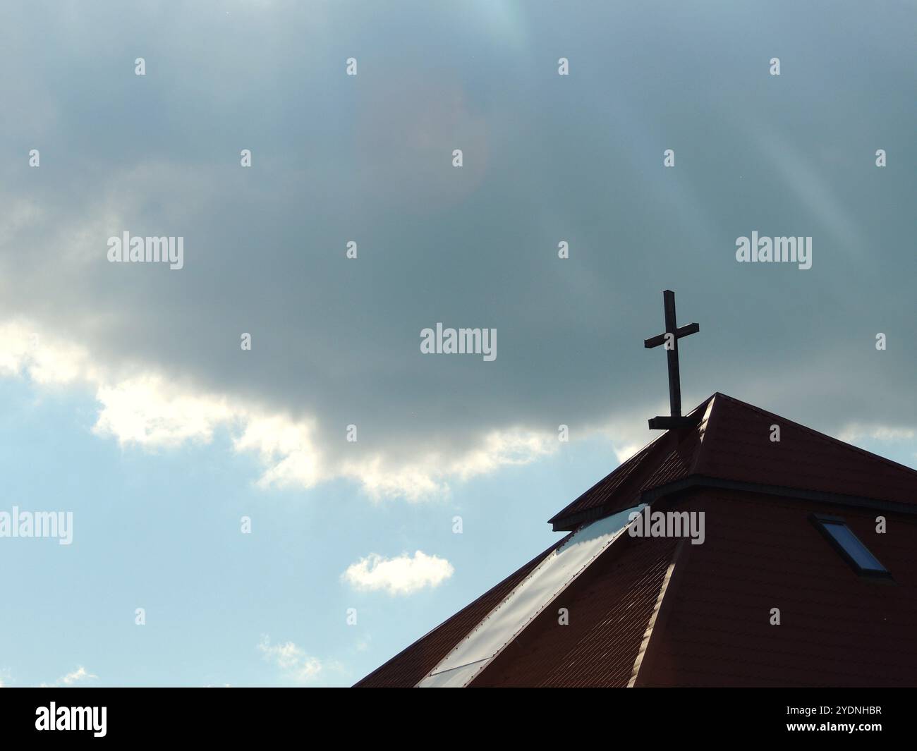 The tiled roof of a Protestant church with a cross on top against a ...
