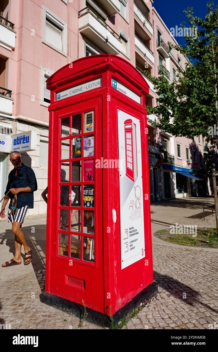Pedestrian walking by red phone booth turned public library, offering ...
