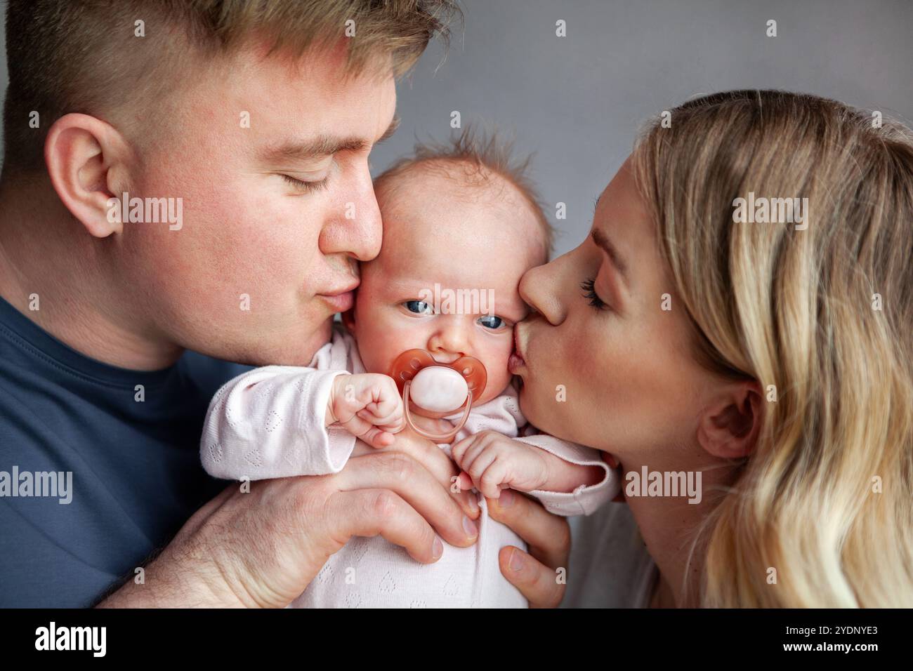 Happy young family. Beautiful Mother and father kissing newborn baby ...