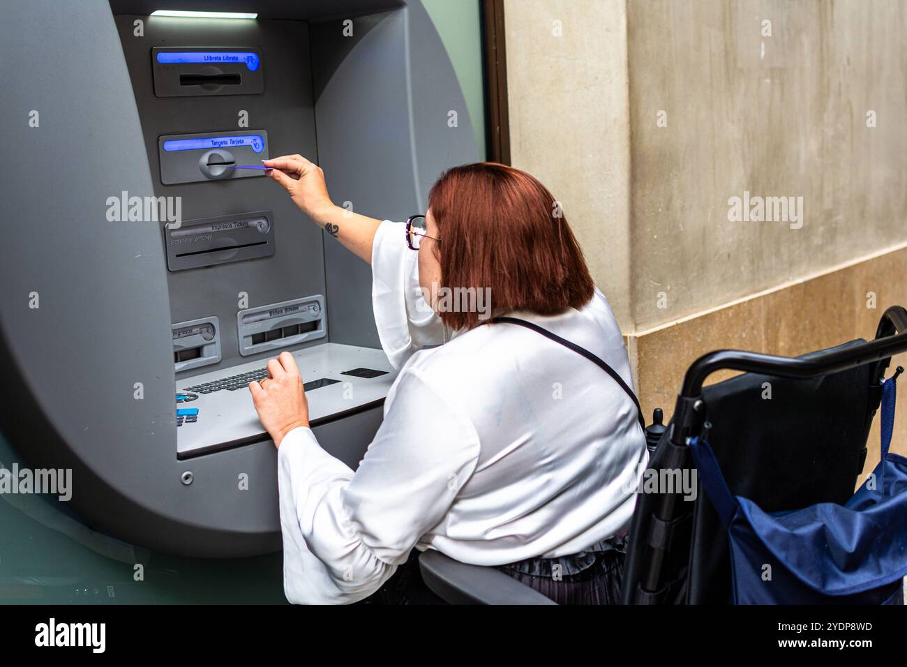 Wheelchair User Inserting Card at City ATM Stock Photo - Alamy
