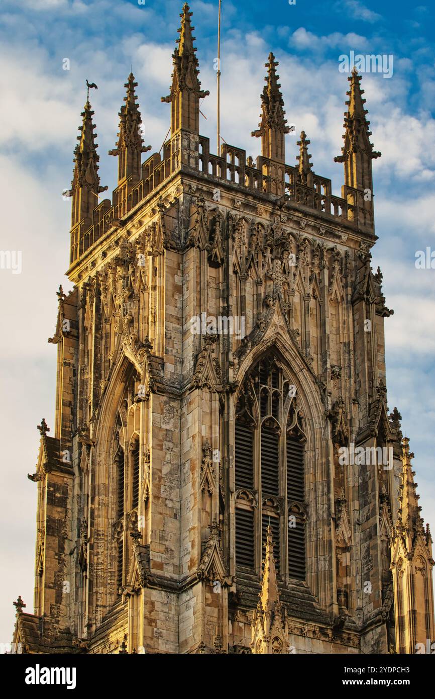 A close-up view of the upper section of a tall, stone cathedral tower ...