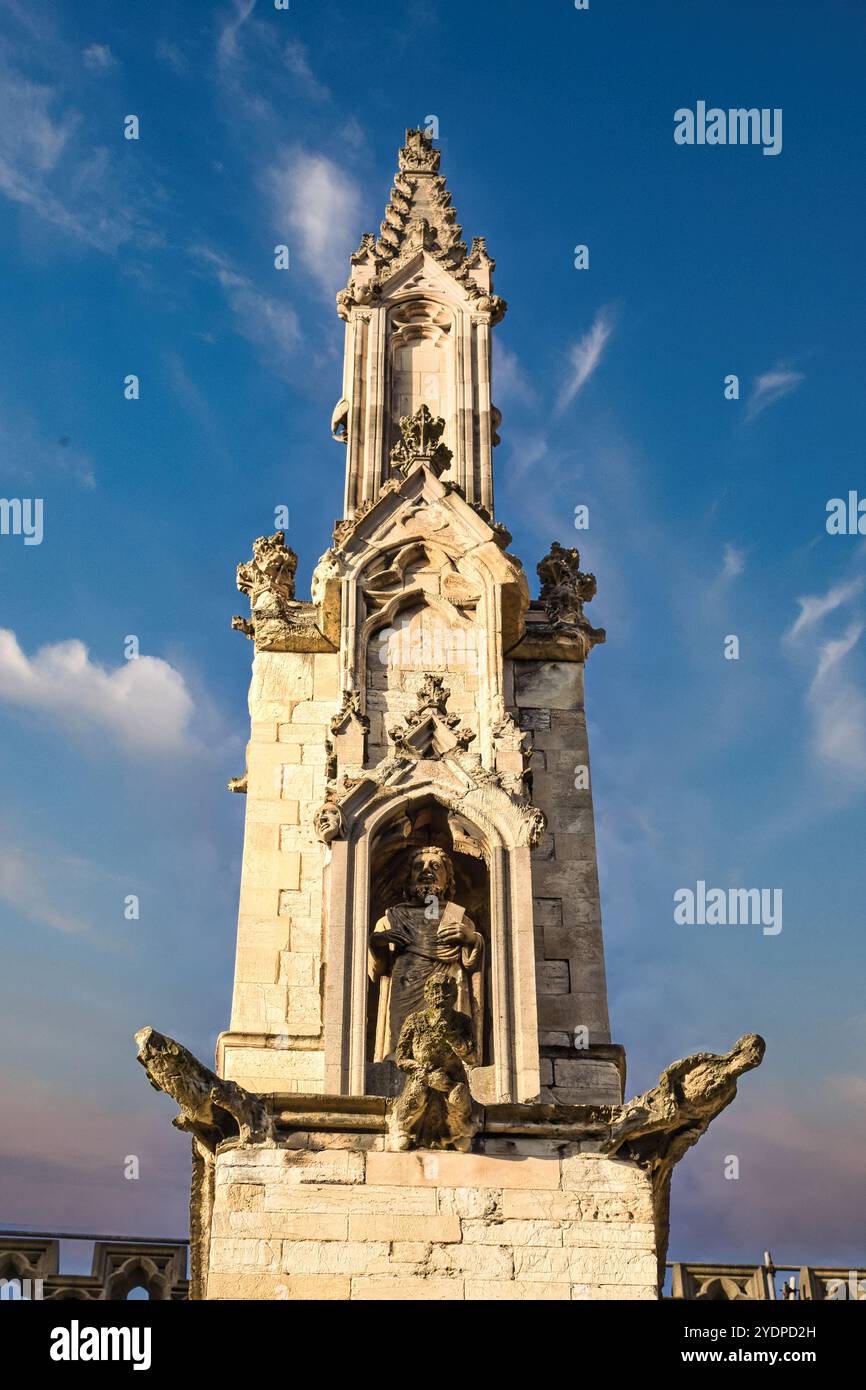 A tall stone spire with intricate carvings and a statue in a niche, set ...