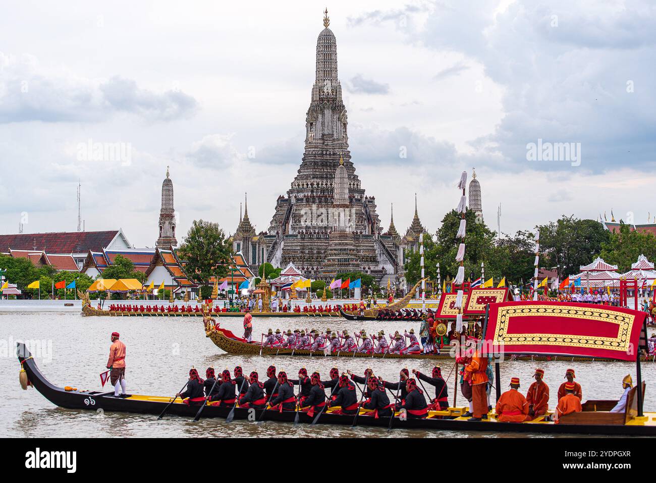Rowers paddle ornate barges down the Chao Phraya River next to Wat Arun ...