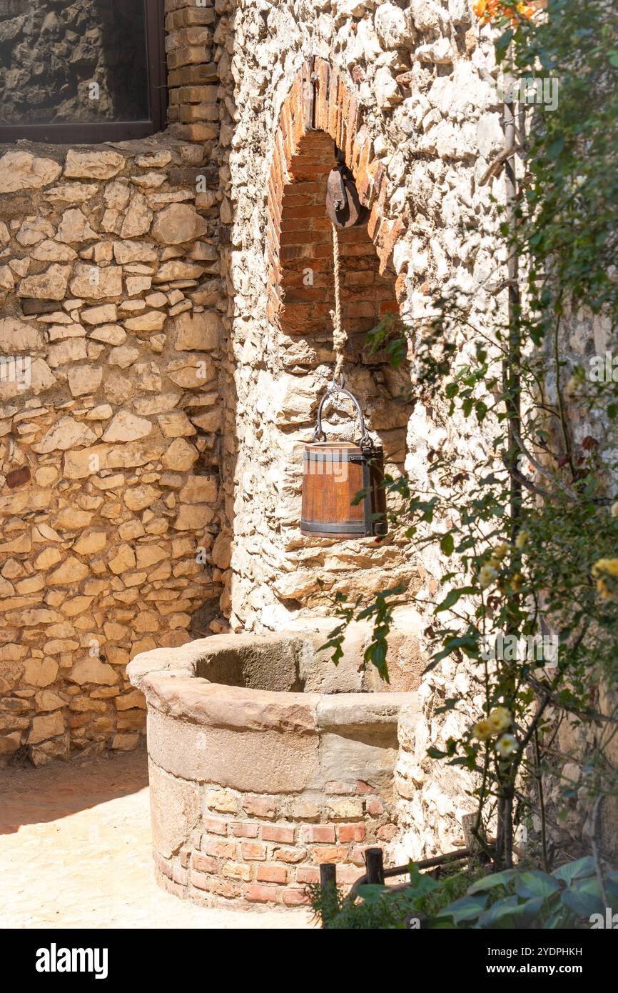 Old stone well with wooden bucket in front of a stone wall Stock Photo ...