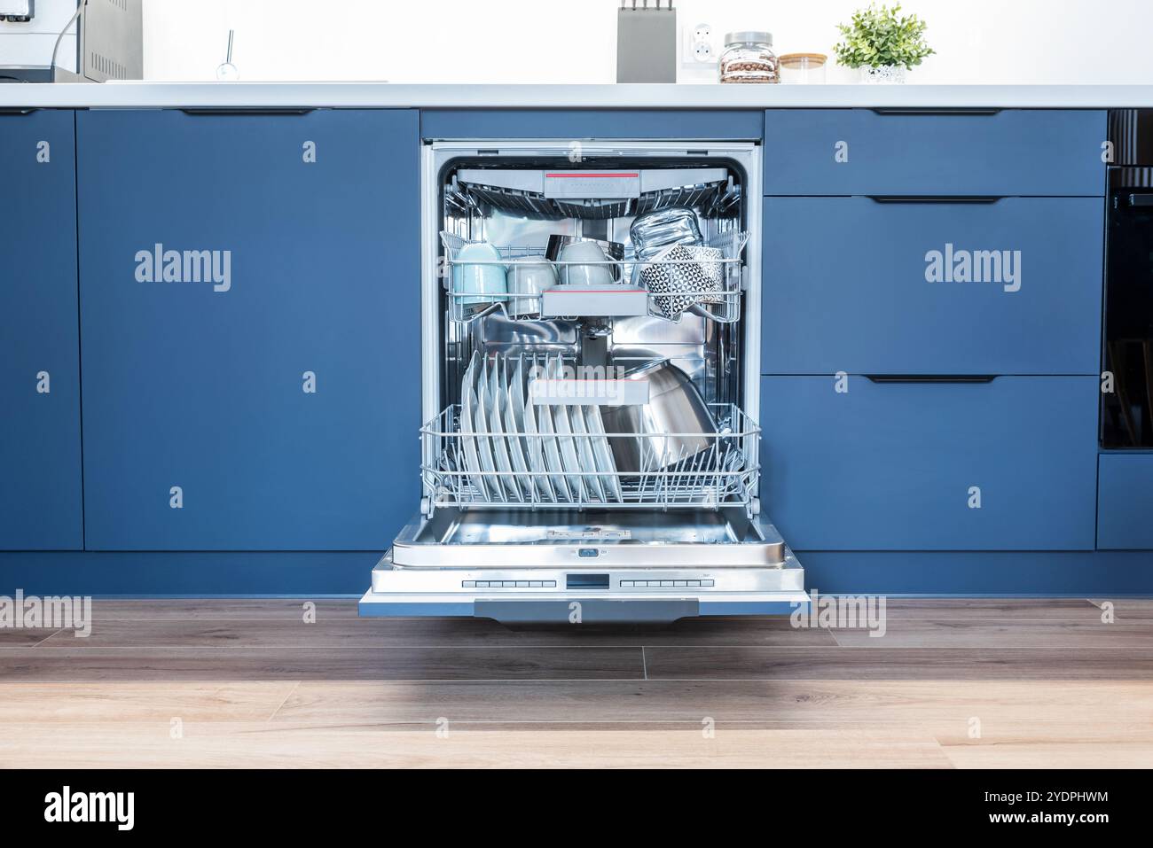 Blue dishwasher in a modern kitchen. The door is open and the inside is ...