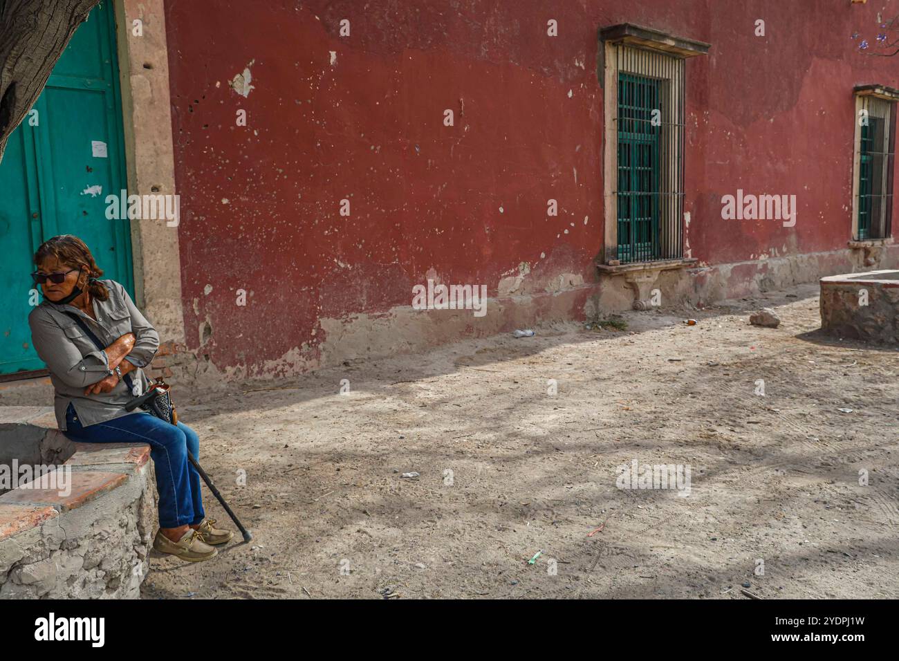 old woman with her cane sitting on the flowerpot at the old Peñasco ...