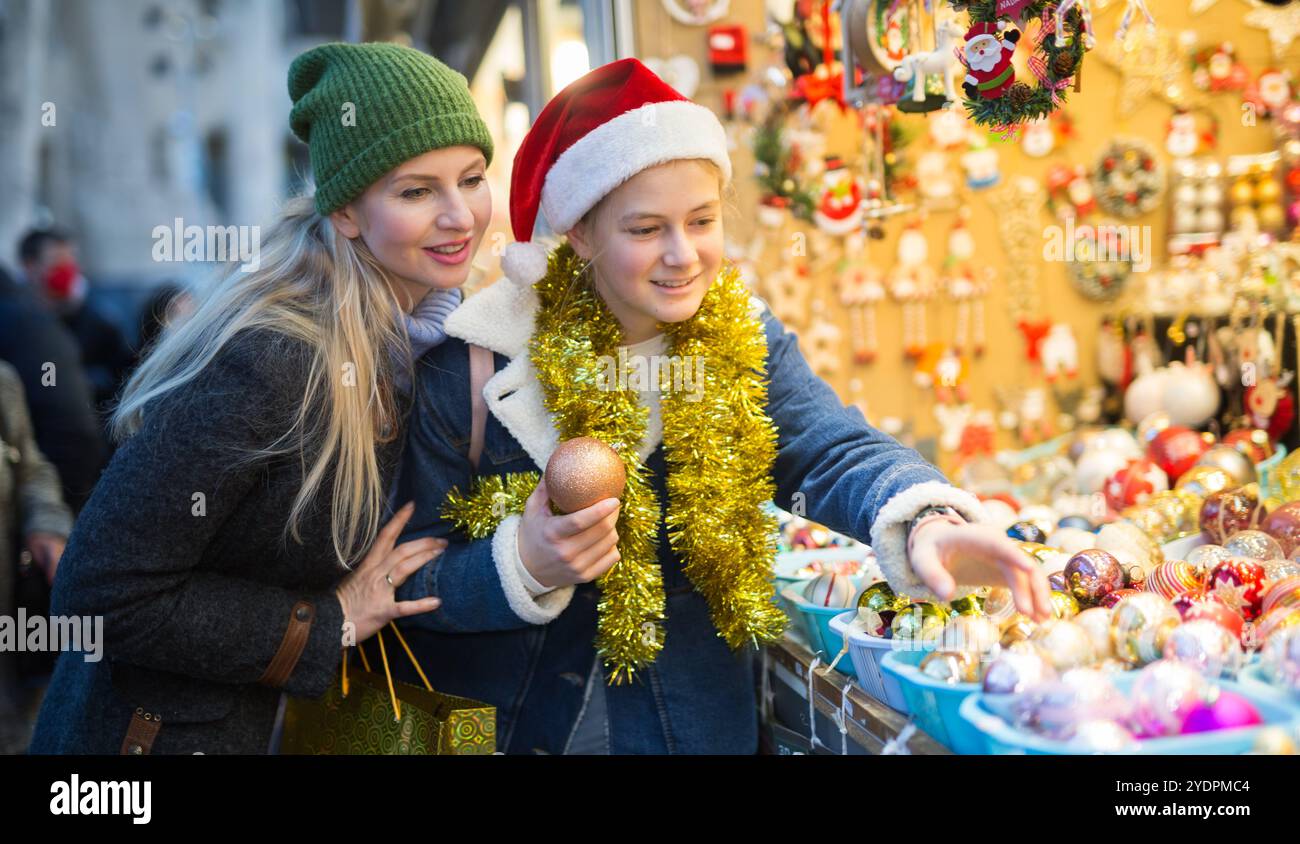 Girl and her mother purchasing decorations at christmas market Stock ...