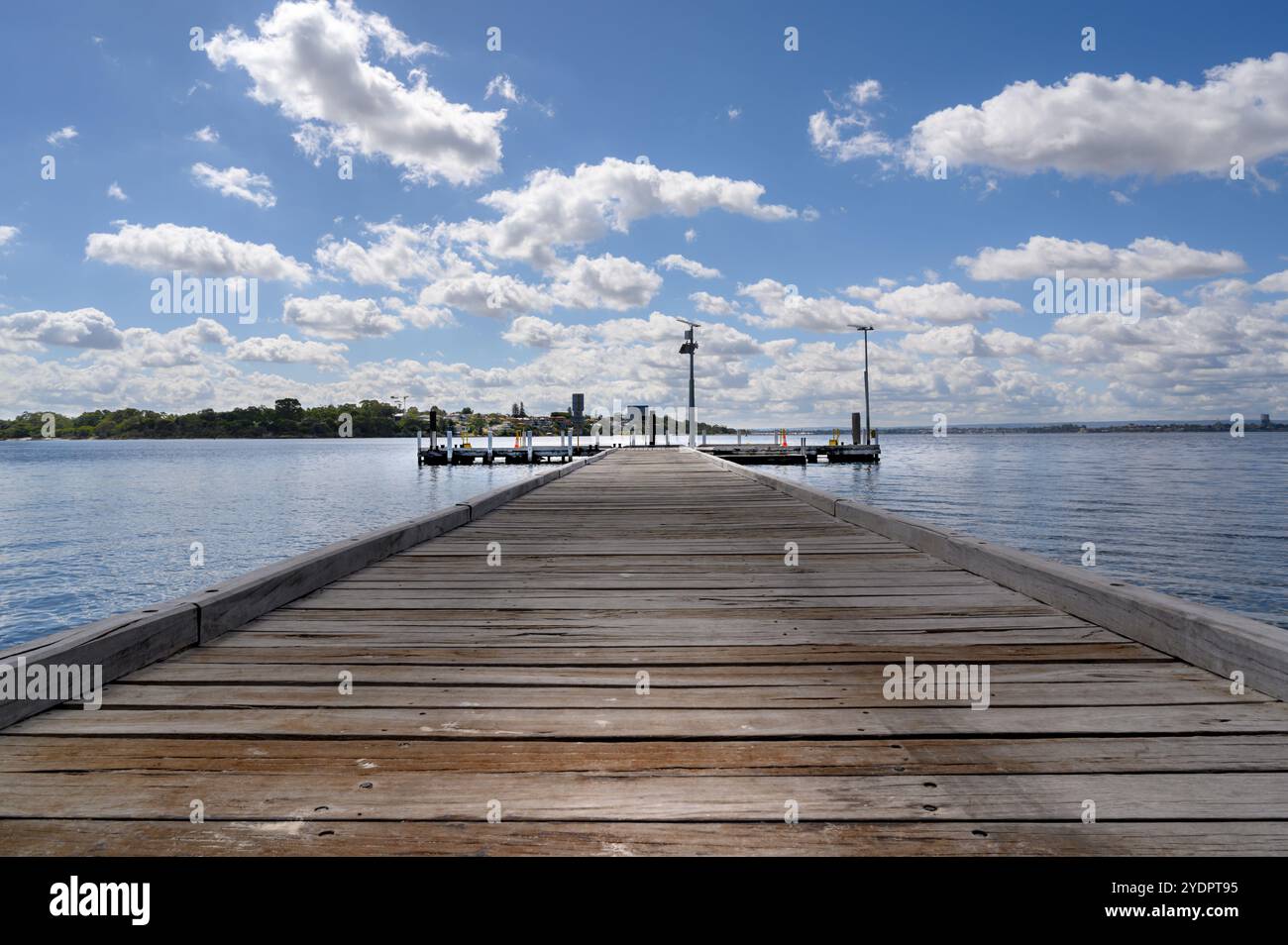 Pier extending out to the river sunny day, blue sky with clouds copy ...
