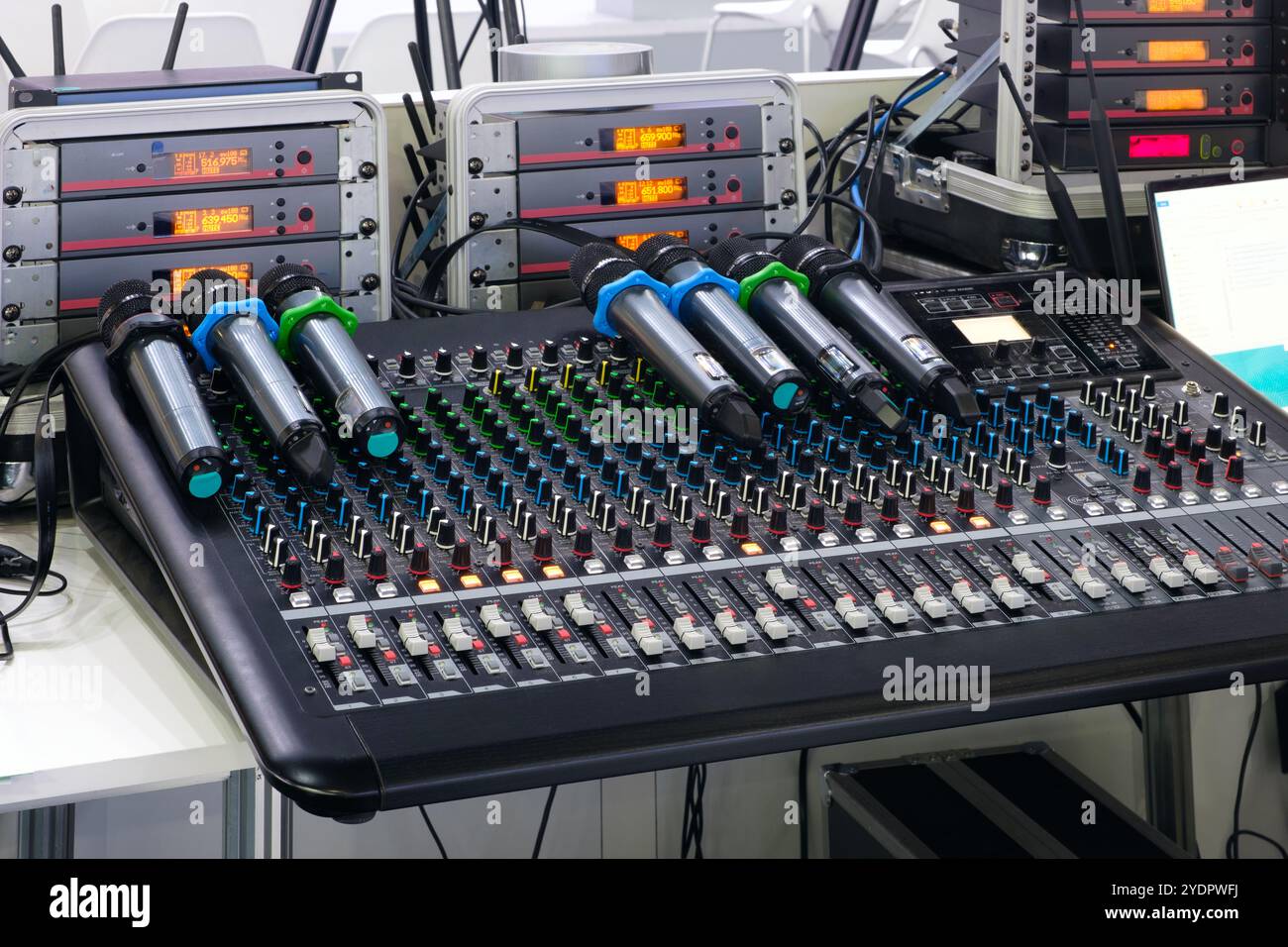 A black mixing board with a microphone stand on it. The stand has a ...