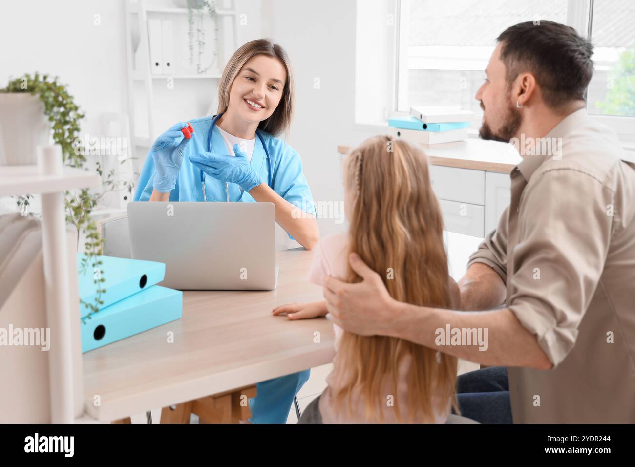 Female endocrinologist working with little girl and father in clinic ...