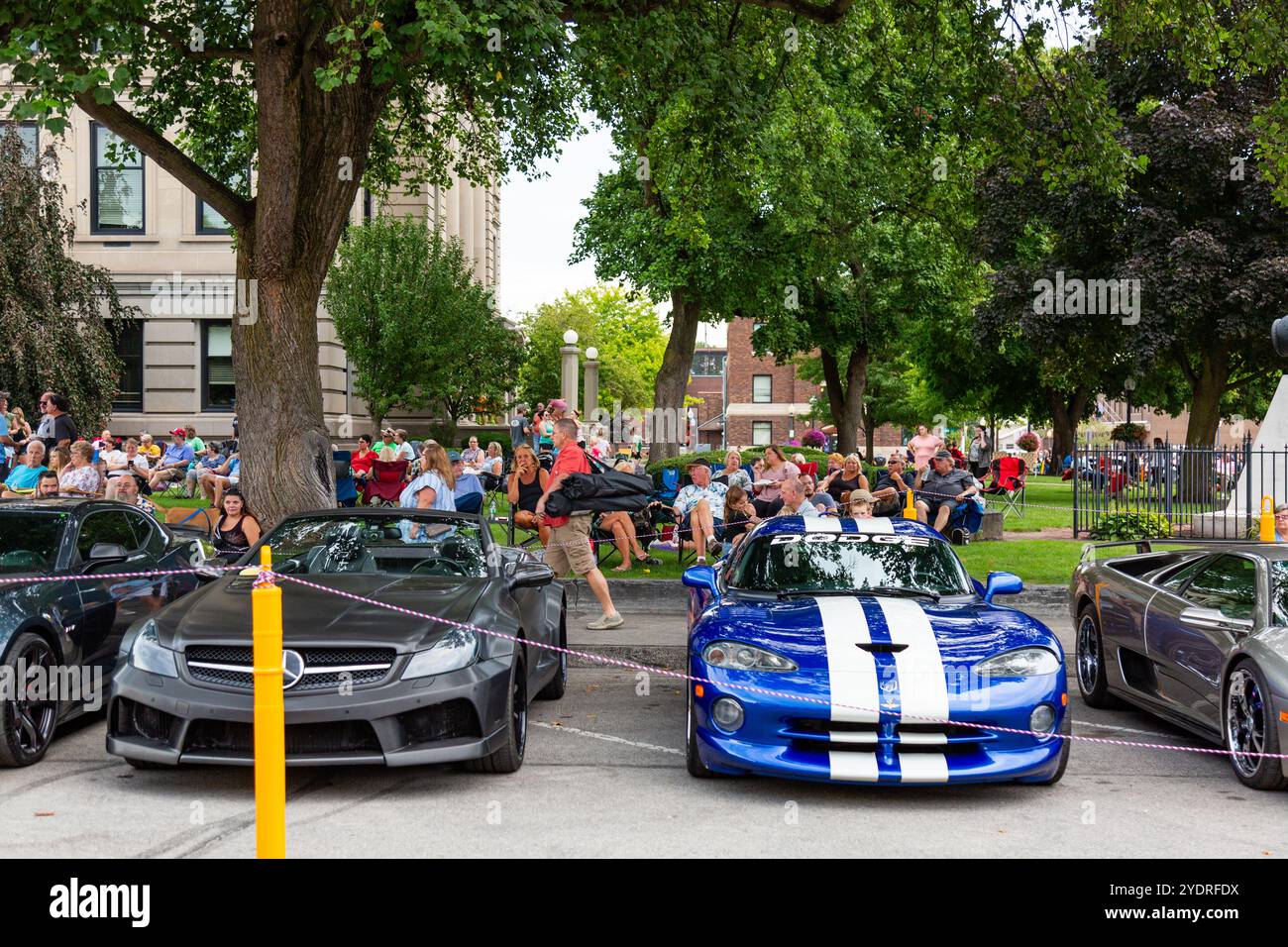 People are gathered behind a gray Mercedes Benz SL convertible & a blue ...