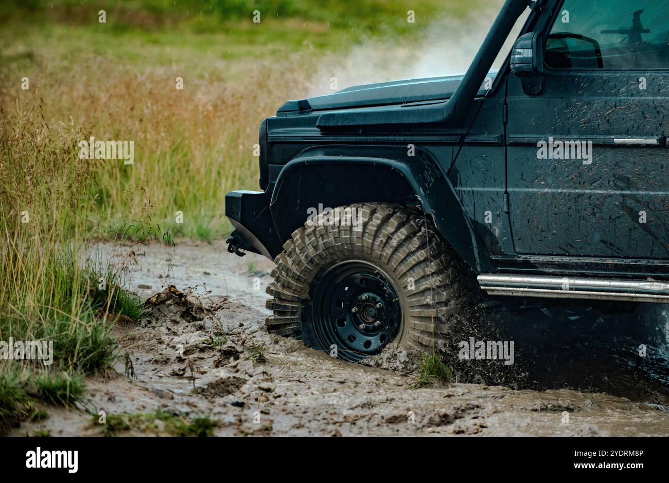 Off road vehicle coming out of a mud hole hazard. Water splash in off ...