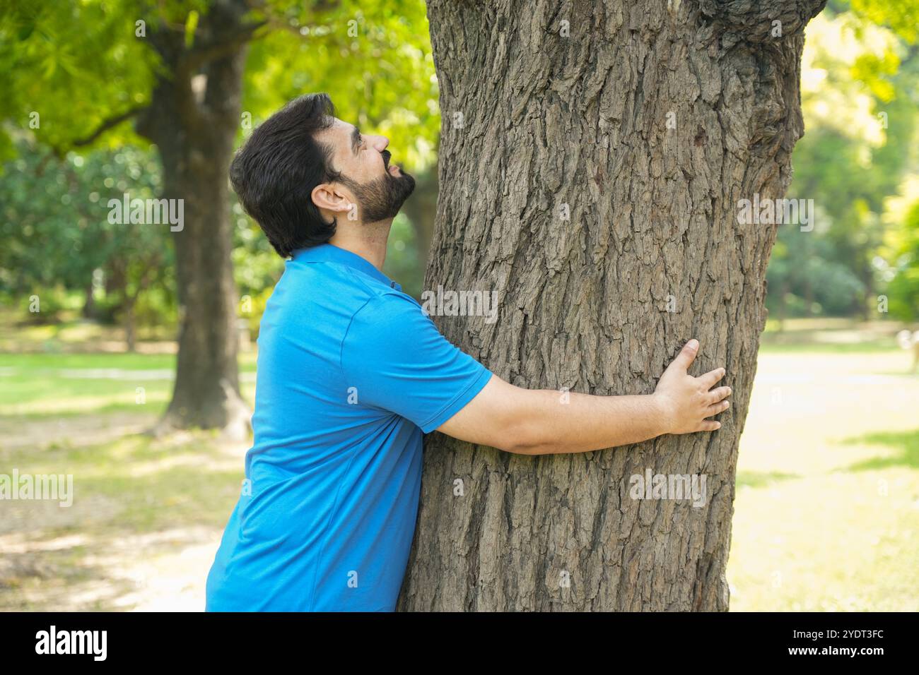 young indian man in forest holding a large tree. Save planet, ecology ...