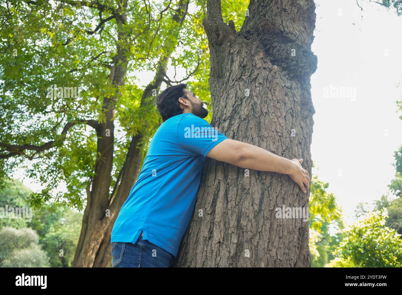 young indian man embracing large tree, Save planet, ecology, climate ...