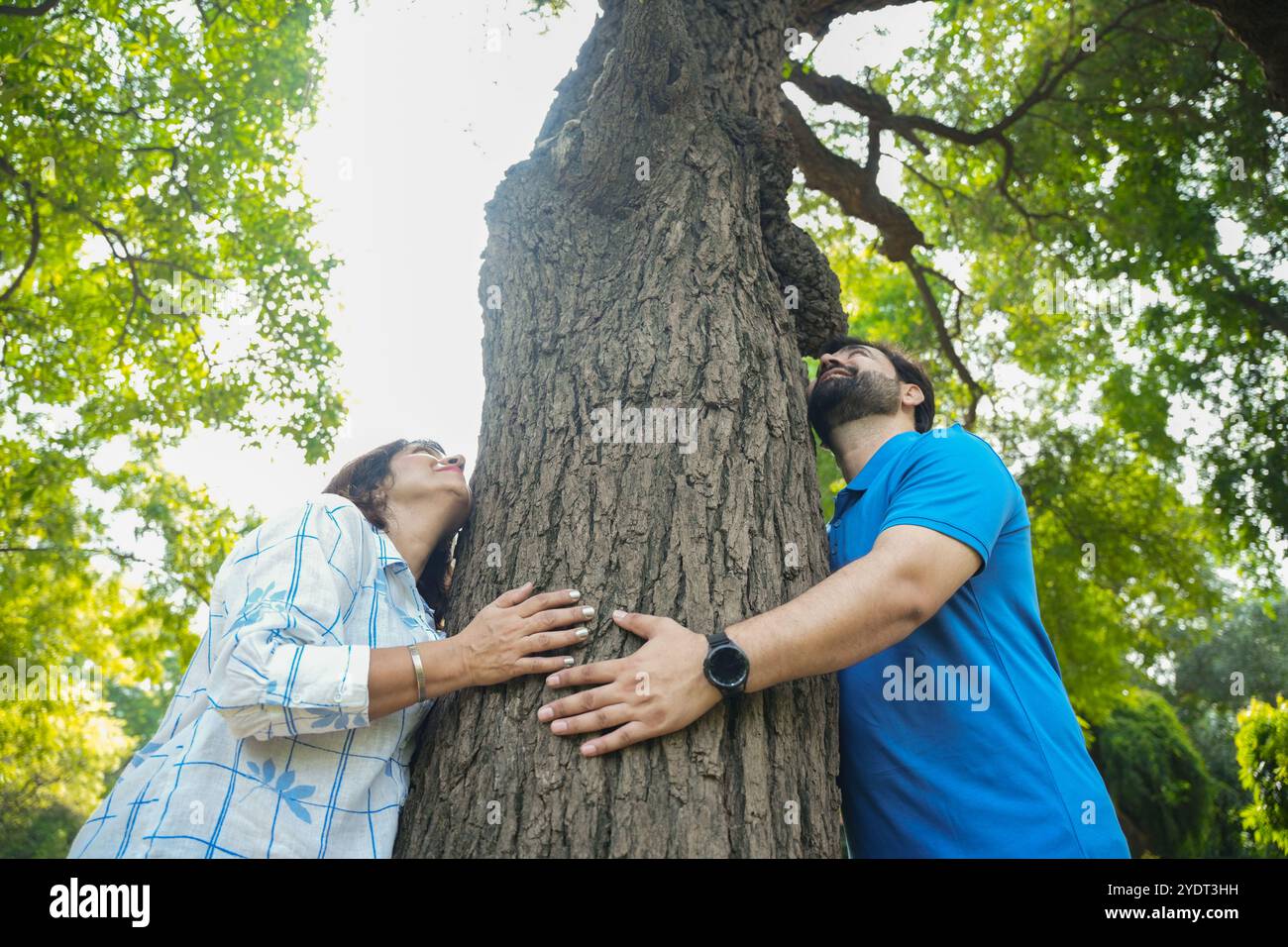 young indian couple in forest hugs large tree, Save environment ...