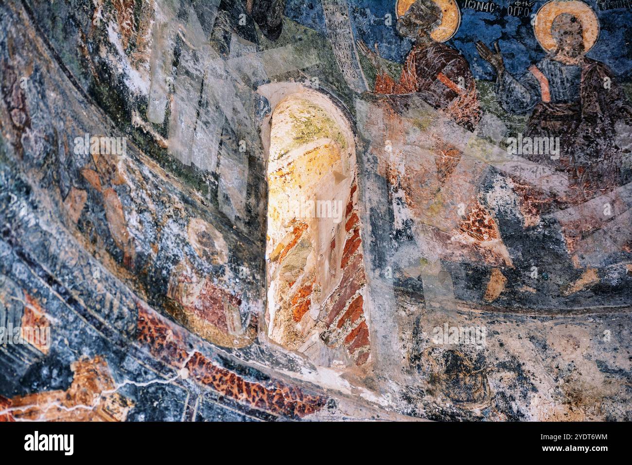 Aged fresco featuring haloed saints next to a narrow, arched stone ...