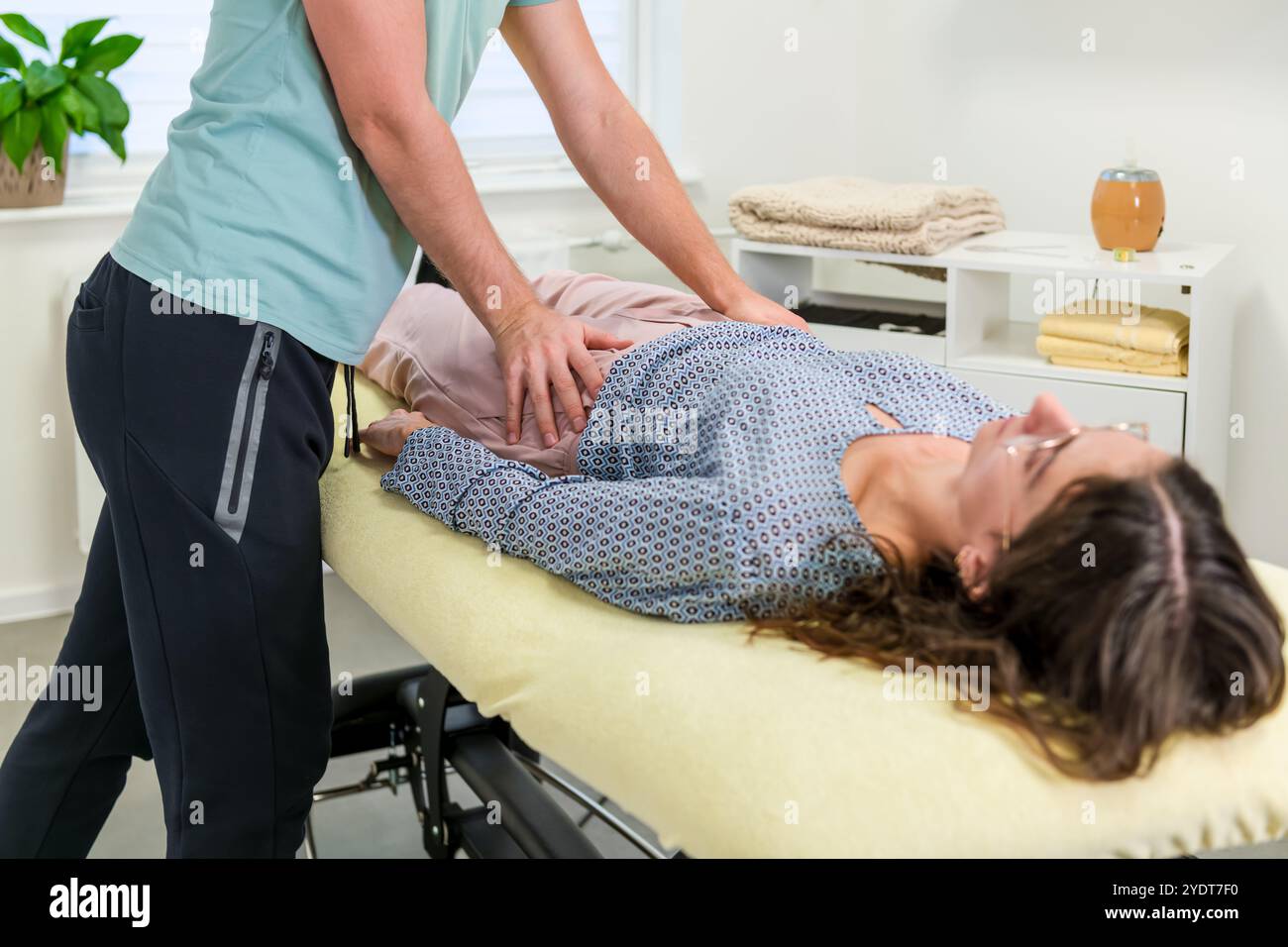 Young woman with back pain in physical therapy. Chiropractor examining ...