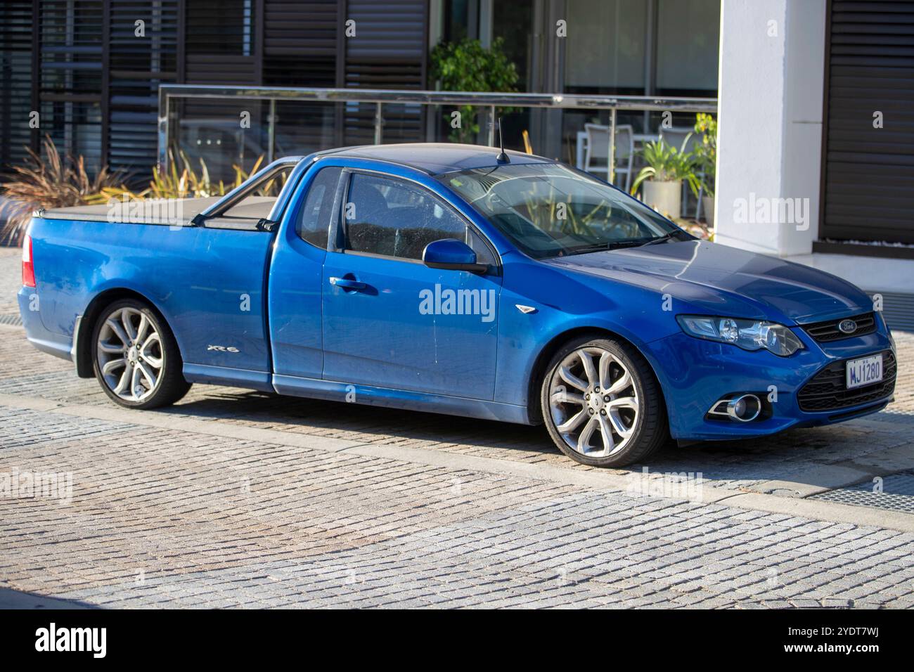 A blue Ford Falcon XR6 Turbo utility vehicle parked on a cobblestone ...