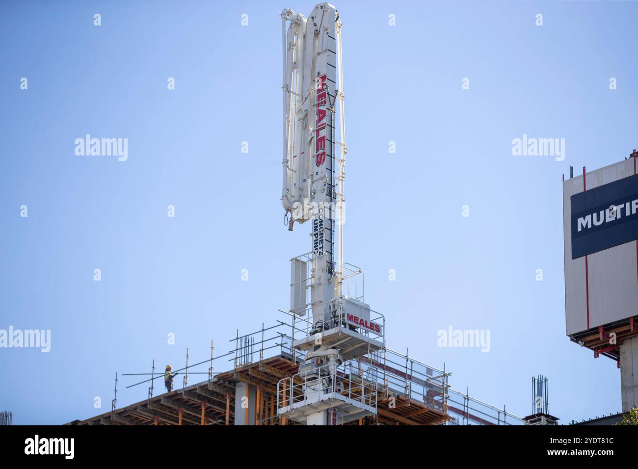 A construction site with a large concrete pumping crane labeled "Meales ...