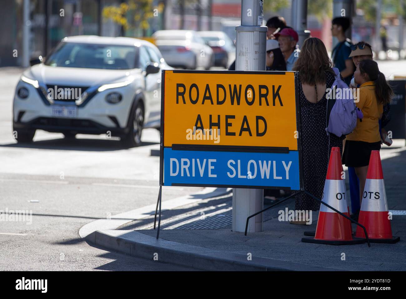 A "Roadwork Ahead" sign with "Drive Slowly" instruction on a busy urban ...