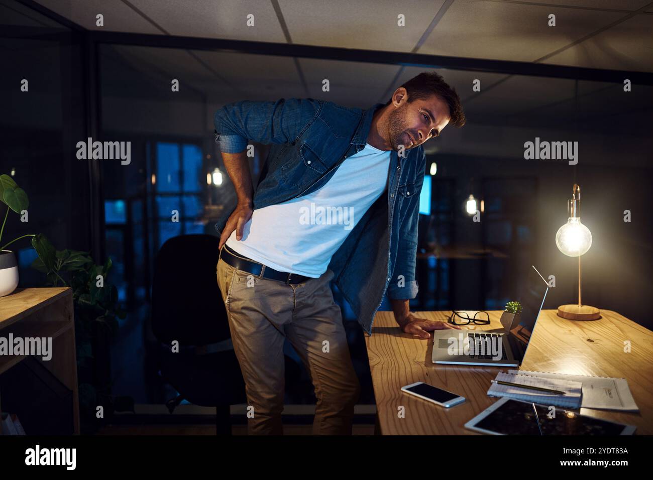 Businessman, laptop and back pain at night in office with fatigue ...