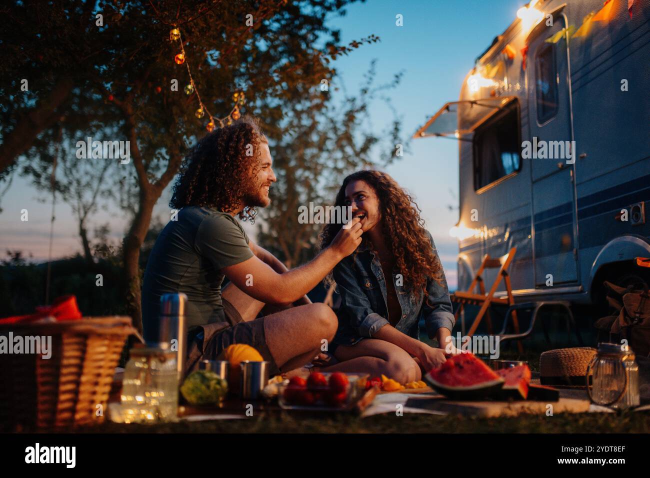 Couple having romantic picnic during camping trip in nature. Man ...
