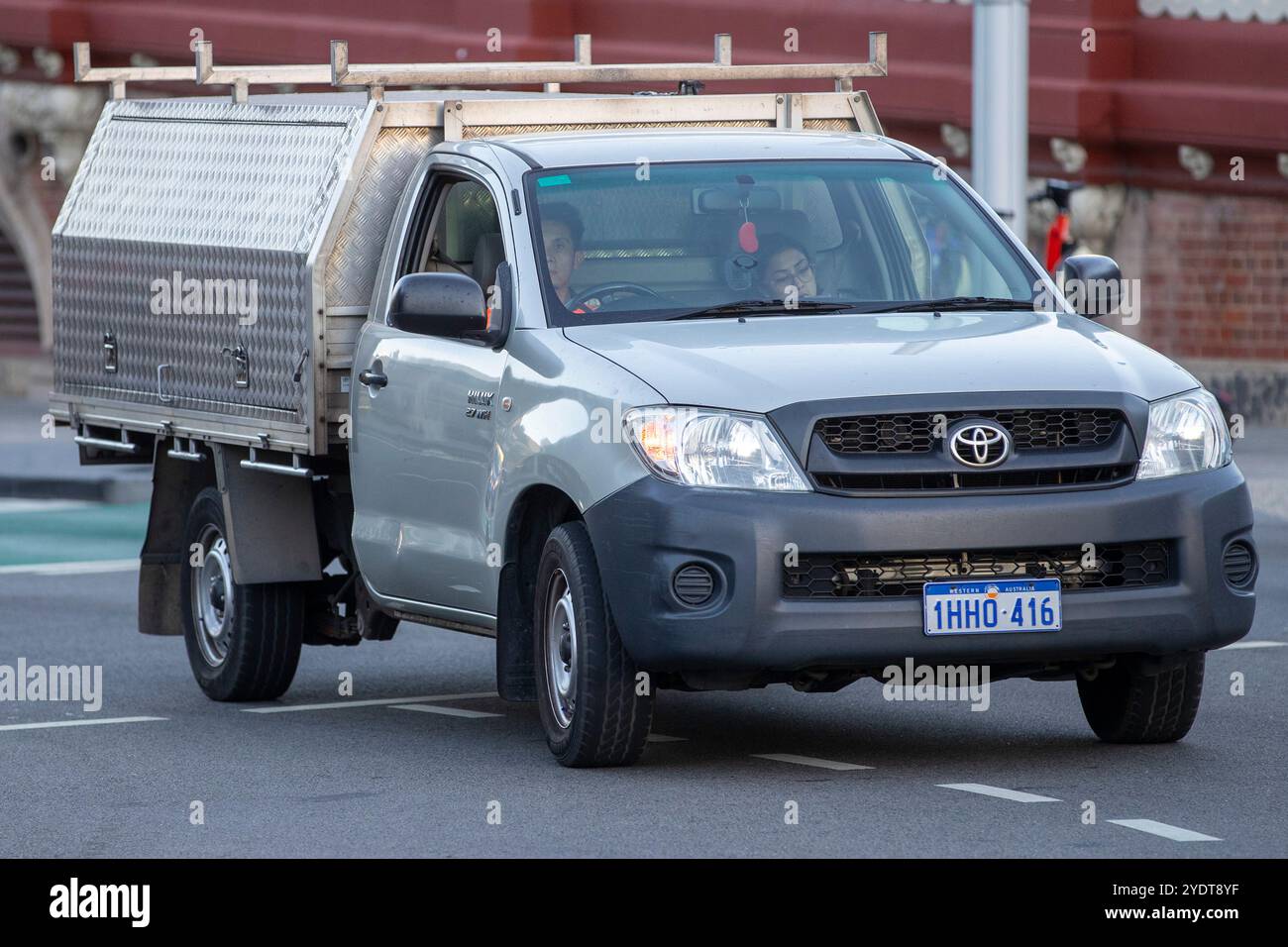A silver Toyota Hilux utility truck driving on a city road, equipped ...