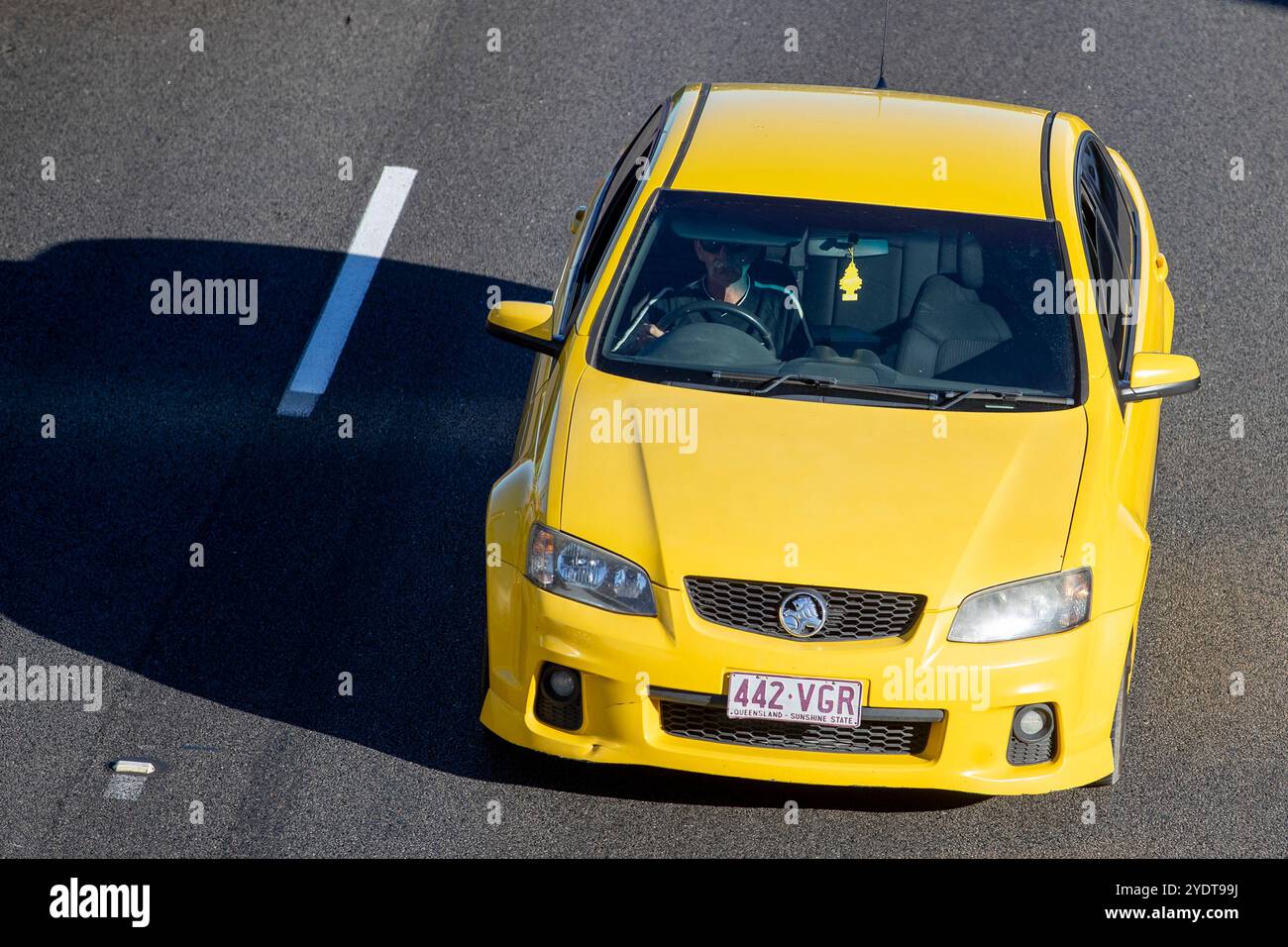 A bright yellow Holden COMMODORE SS–V REDLINE EDITION sedan driving on ...
