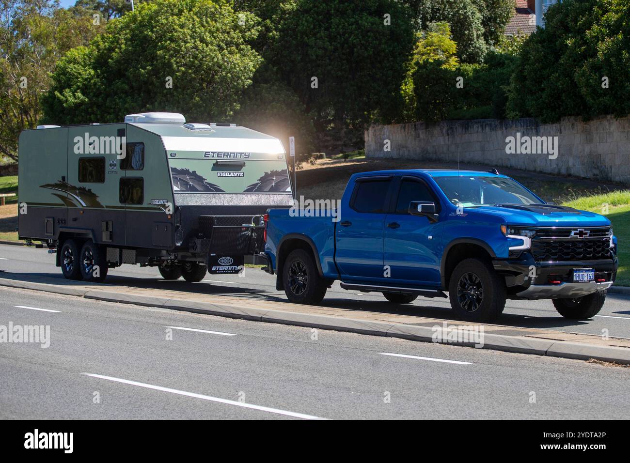 A bright blue Chevrolet Silverado ZR2 pickup truck towing a large ...