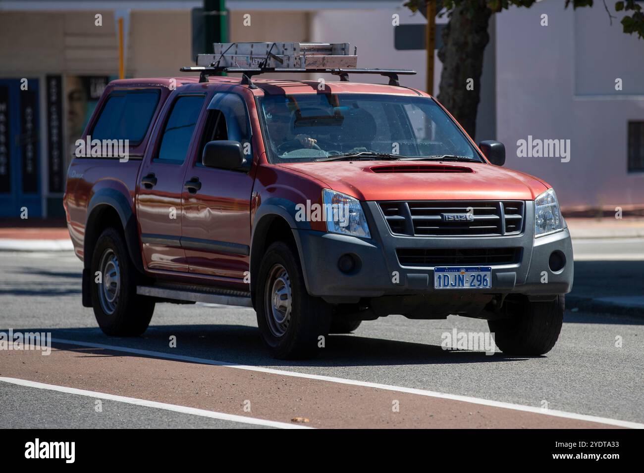 A copper-red Isuzu D-Max utility vehicle equipped with a roof rack ...