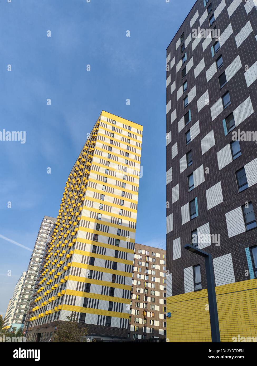 Two modern high-rise apartment buildings, one with a yellow and white ...