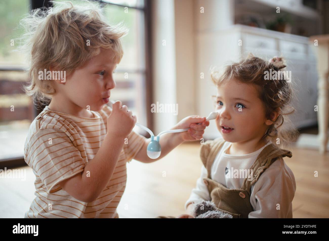 Boy using nasal suction bulb to clear mucus from sisters nose Stock ...