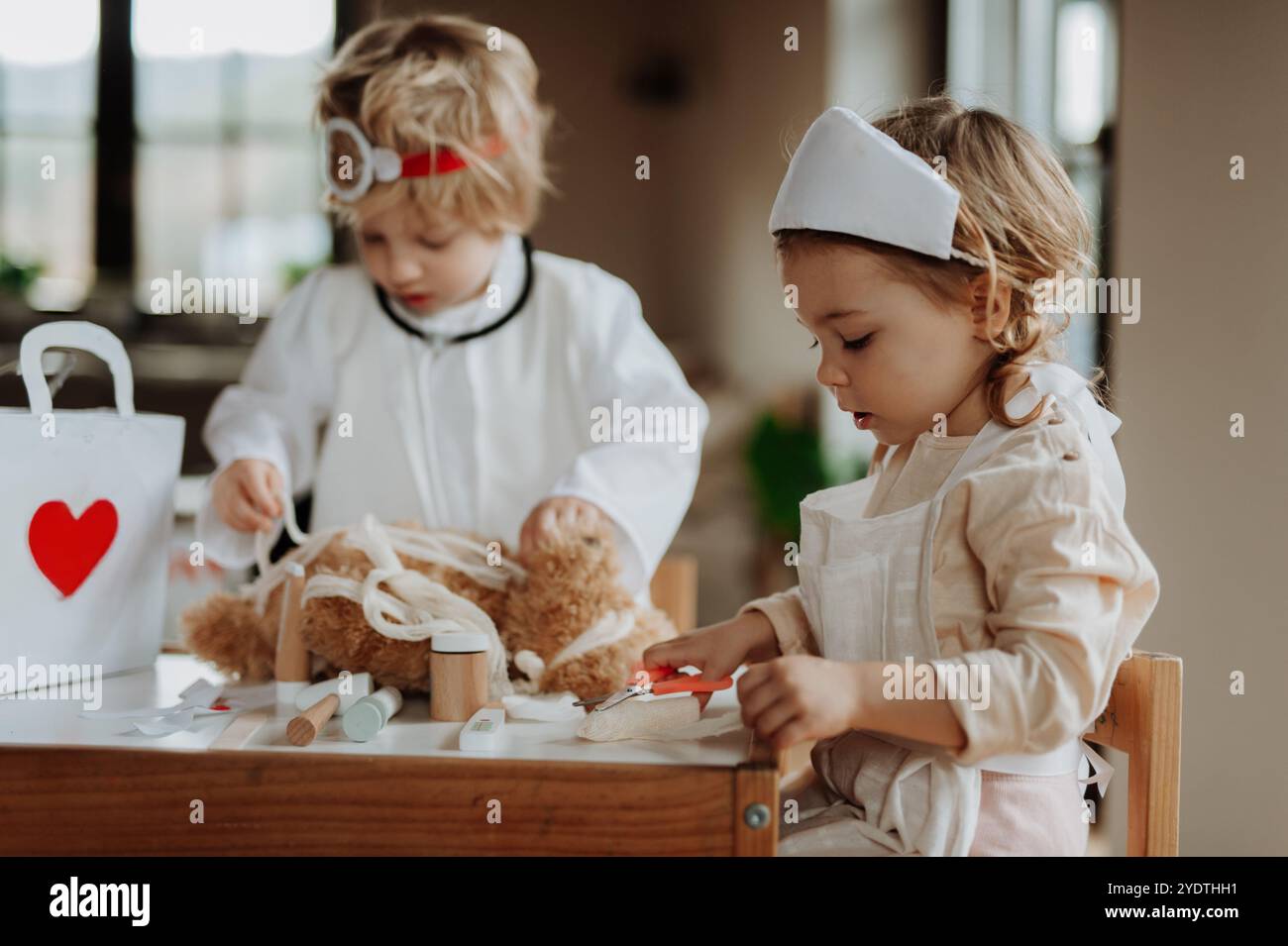 Siblings in doctor uniforms are playing hospital, taking care of sick ...