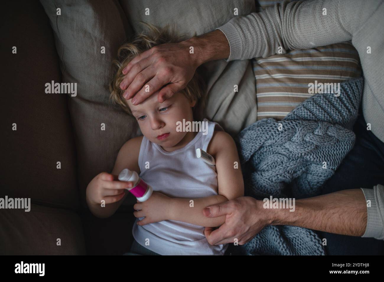 Father taking care of sick son with fever and cold, holdig cold cloth ...