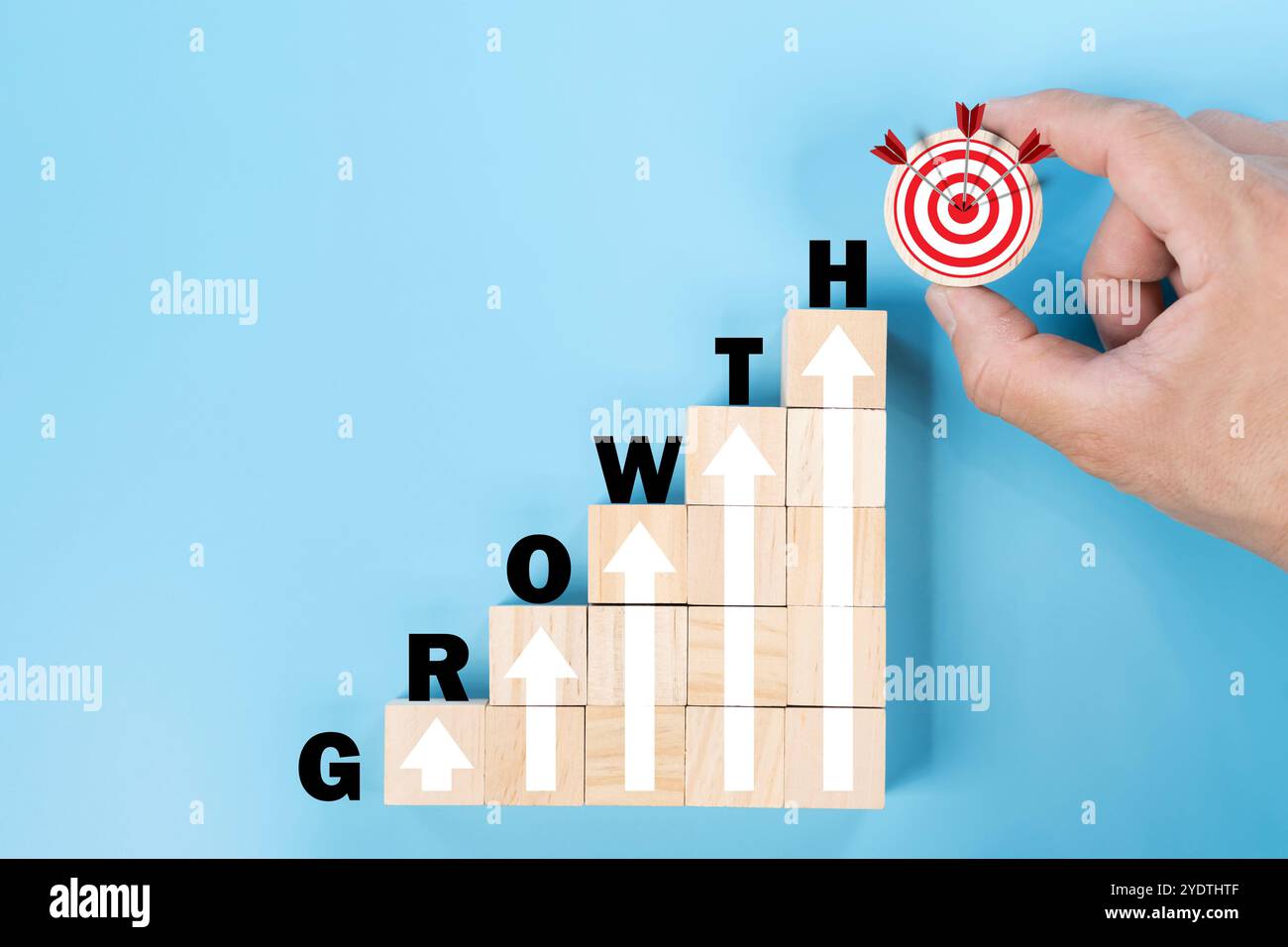 Hand holding wooden block with target aiming dart board and arrow up on ...