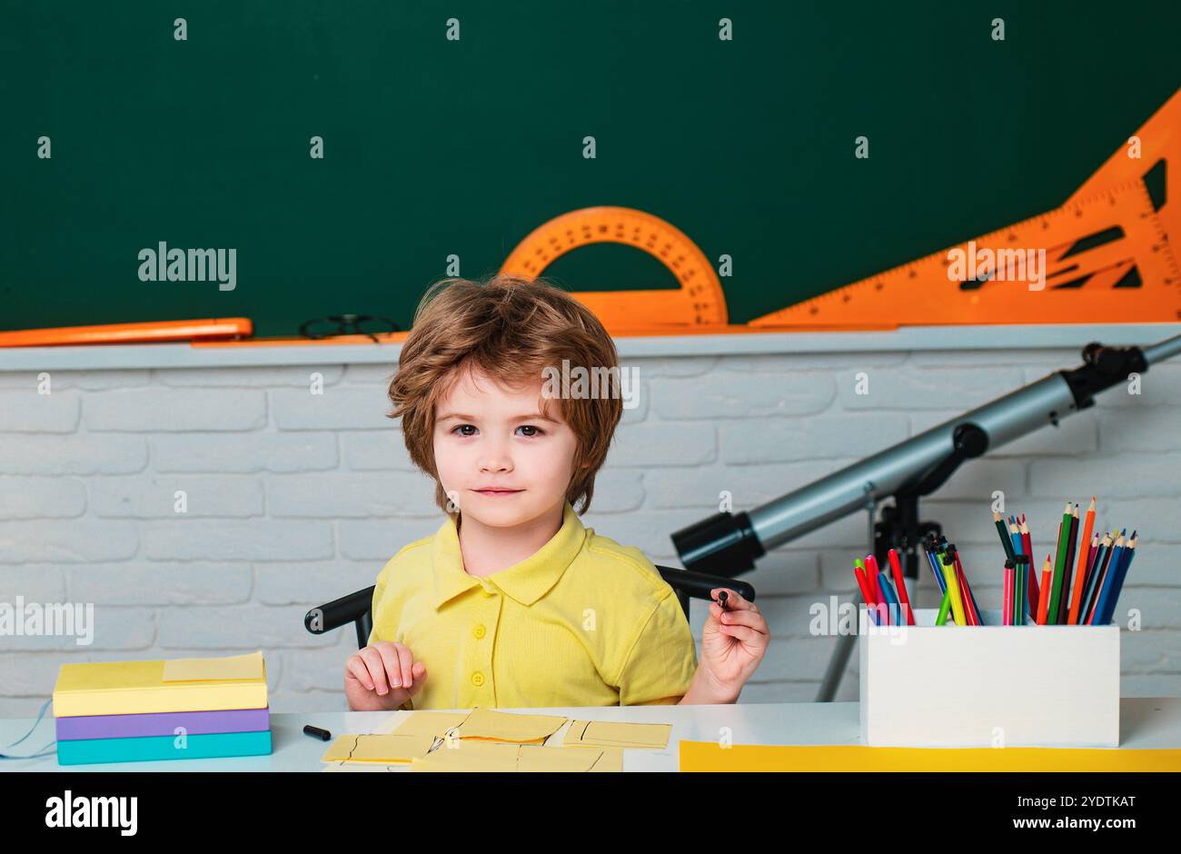 Happy smiling pupil drawing at the desk. First school day. Schoolkid or ...