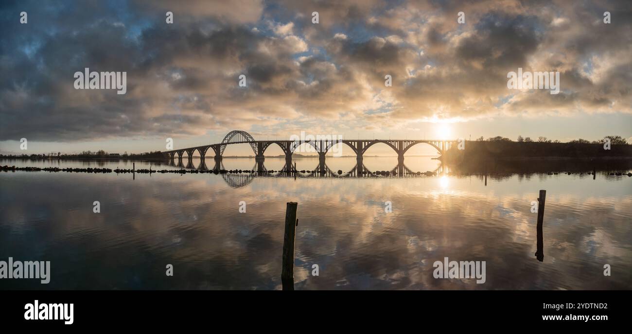Dramatic sunset sky over a calm harbor, with boats docked along the ...